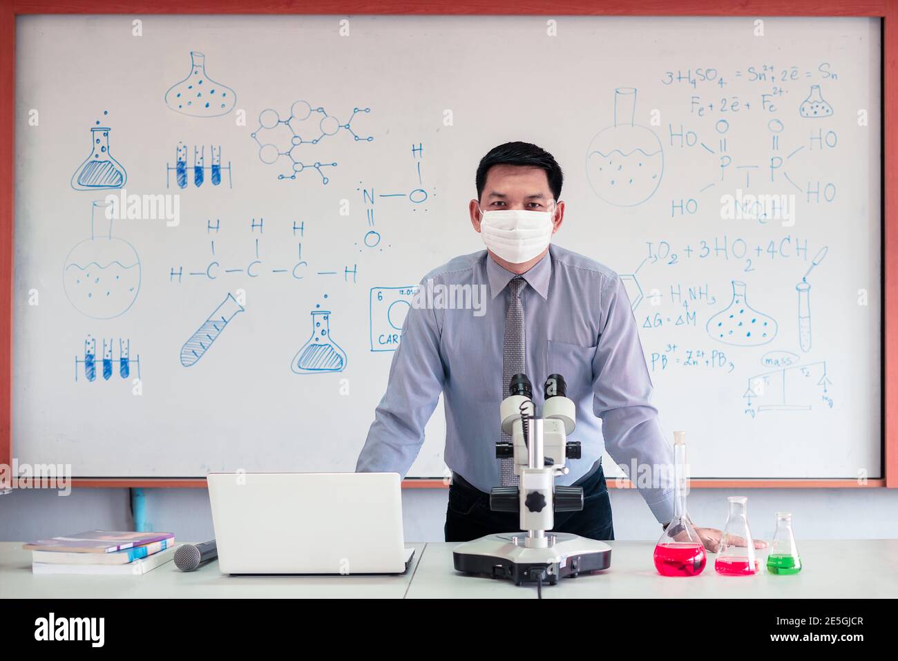 Science chemistry teacher teaching with microscope and laptop in the ...