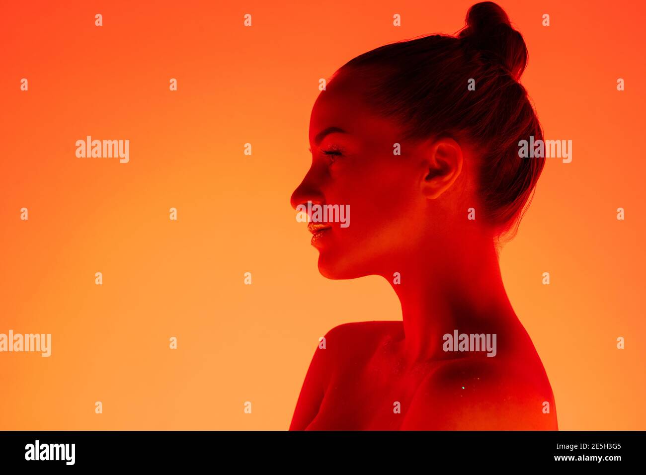 Warm. Handsome woman's portrait isolated on orange studio background in ...