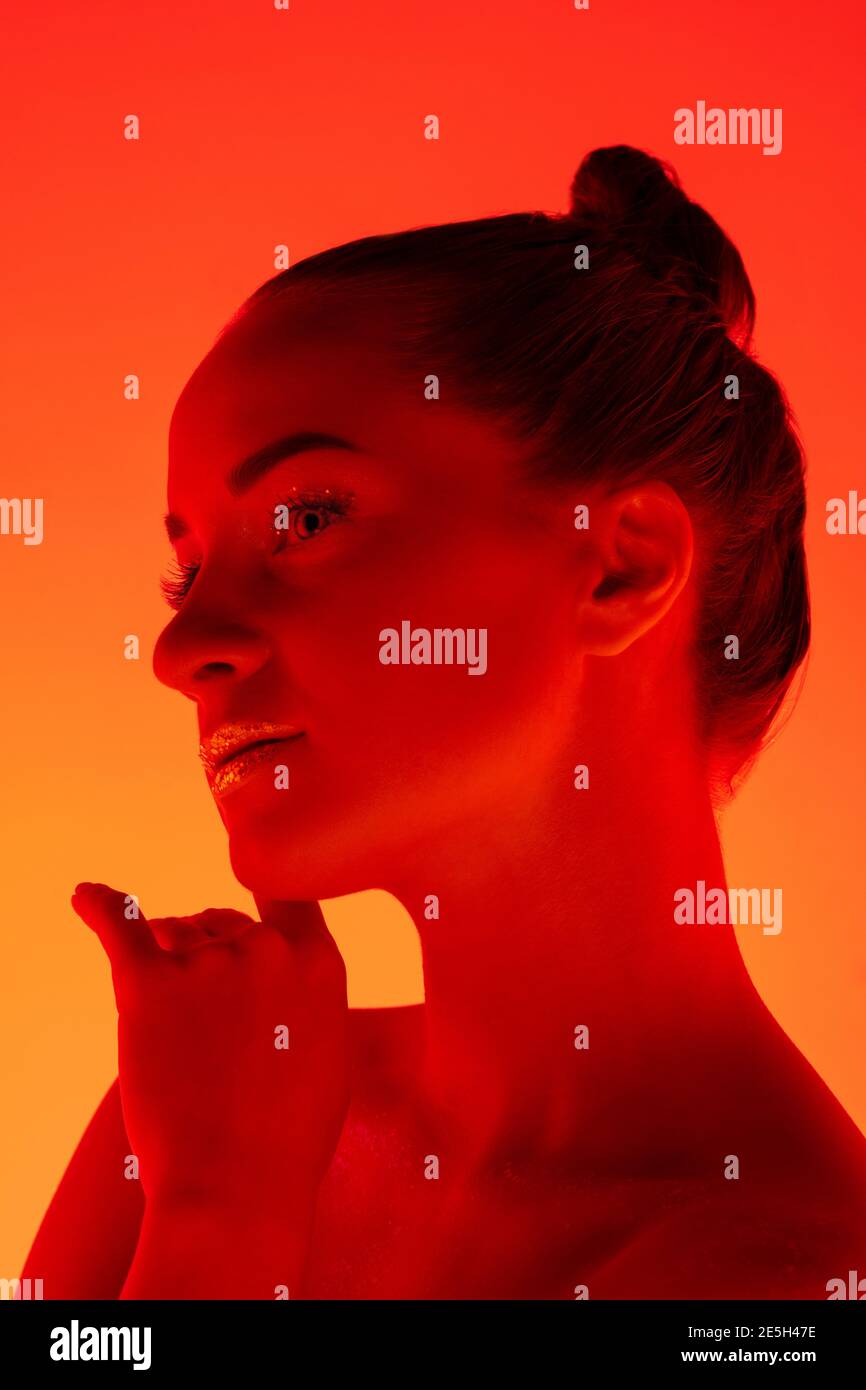 Warm. Handsome woman's portrait isolated on orange studio background in ...