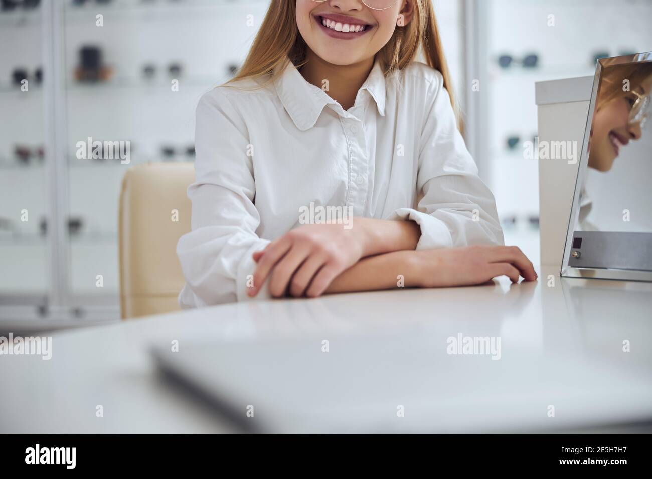 Good looking school girl spending time at the desk in optician center ...