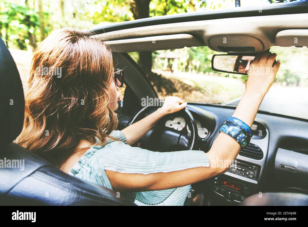 Woman in the car setting car rear view mirror. Pretty young woman ...