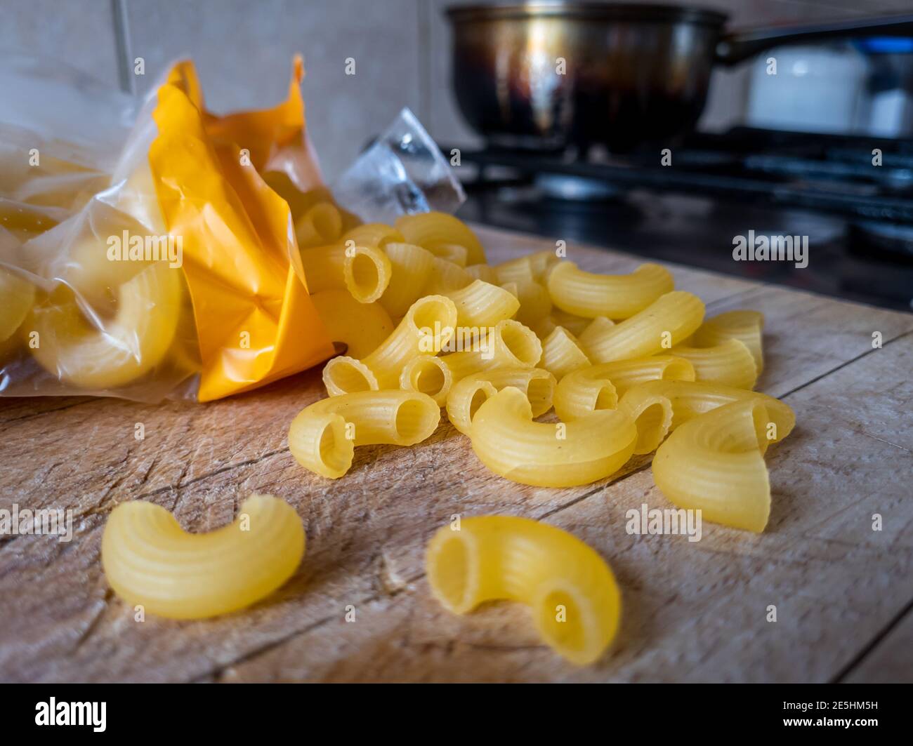 A opened packet of macaroni on a wooden board Stock Photo - Alamy