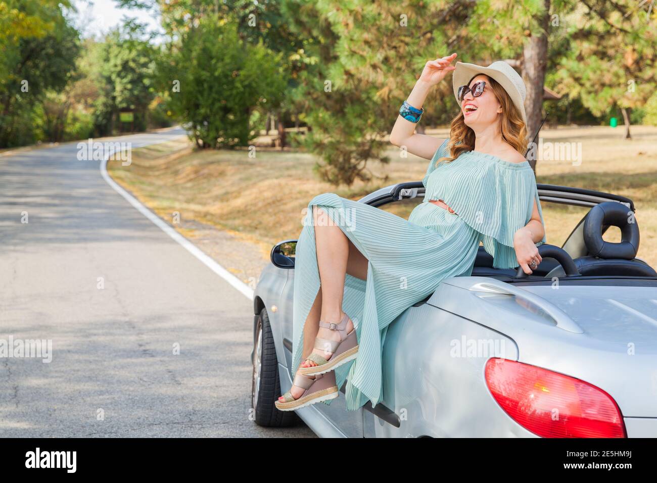 Attractive woman leaning and posing at convertible car. Happy pretty ...