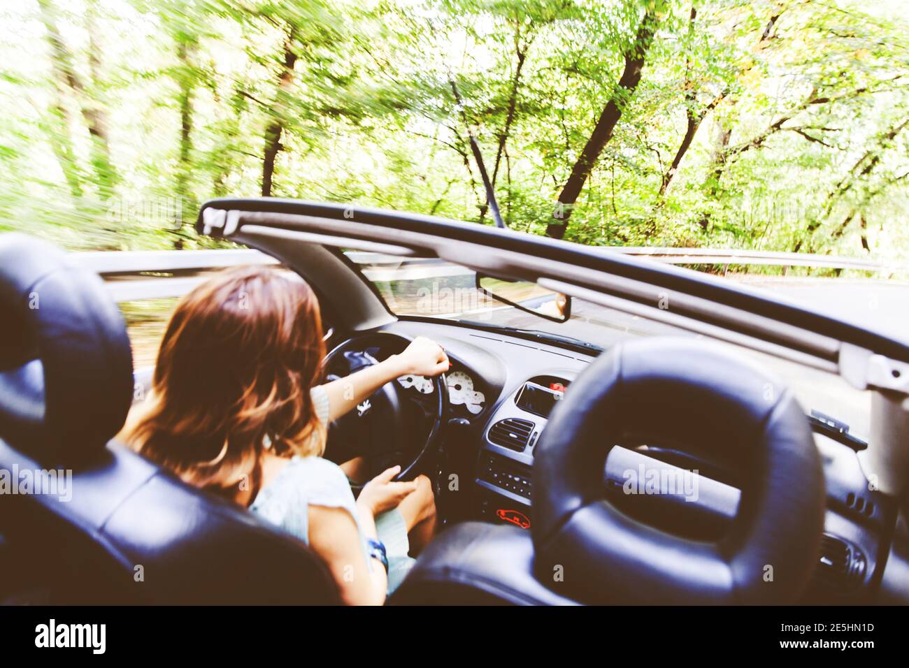 Pretty young woman driving convertible car on summer day. Wearing ...