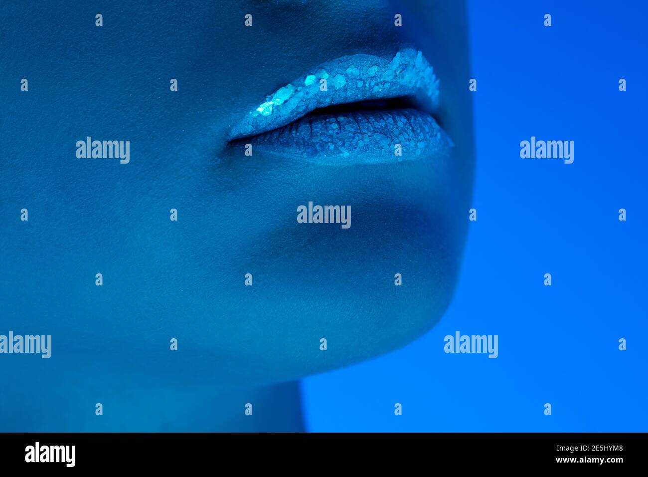 Close up female lips and cheeks isolated on blue studio background in ...