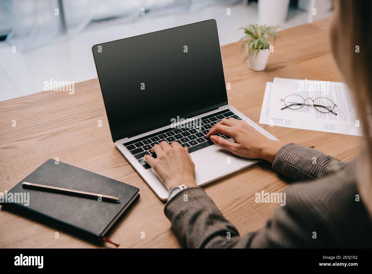 cropped view of businesswoman typing on laptop at workplace with ...