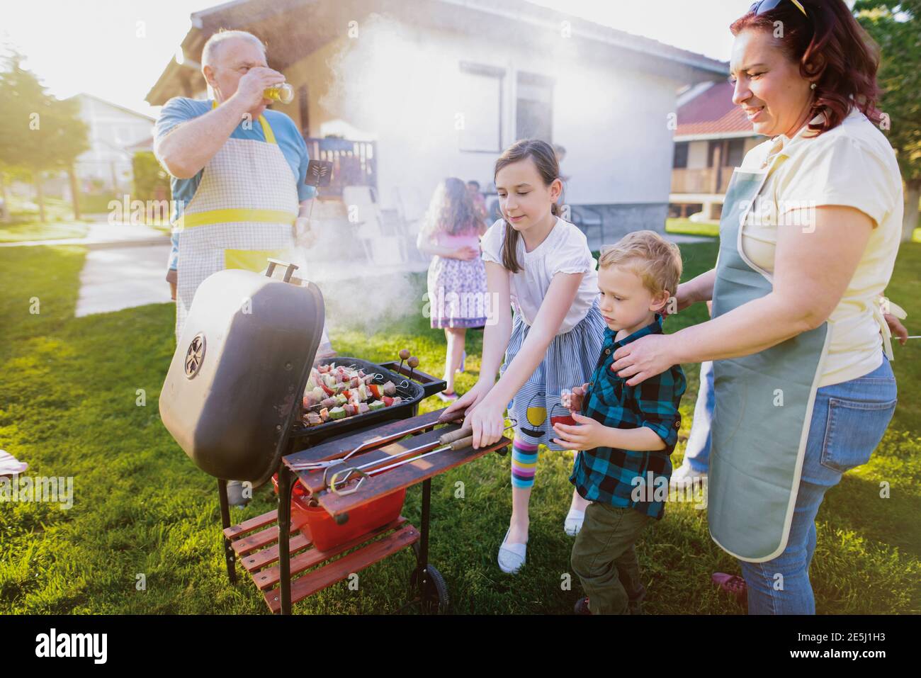 Young girl learning how to make a barbeque while their mother is ...