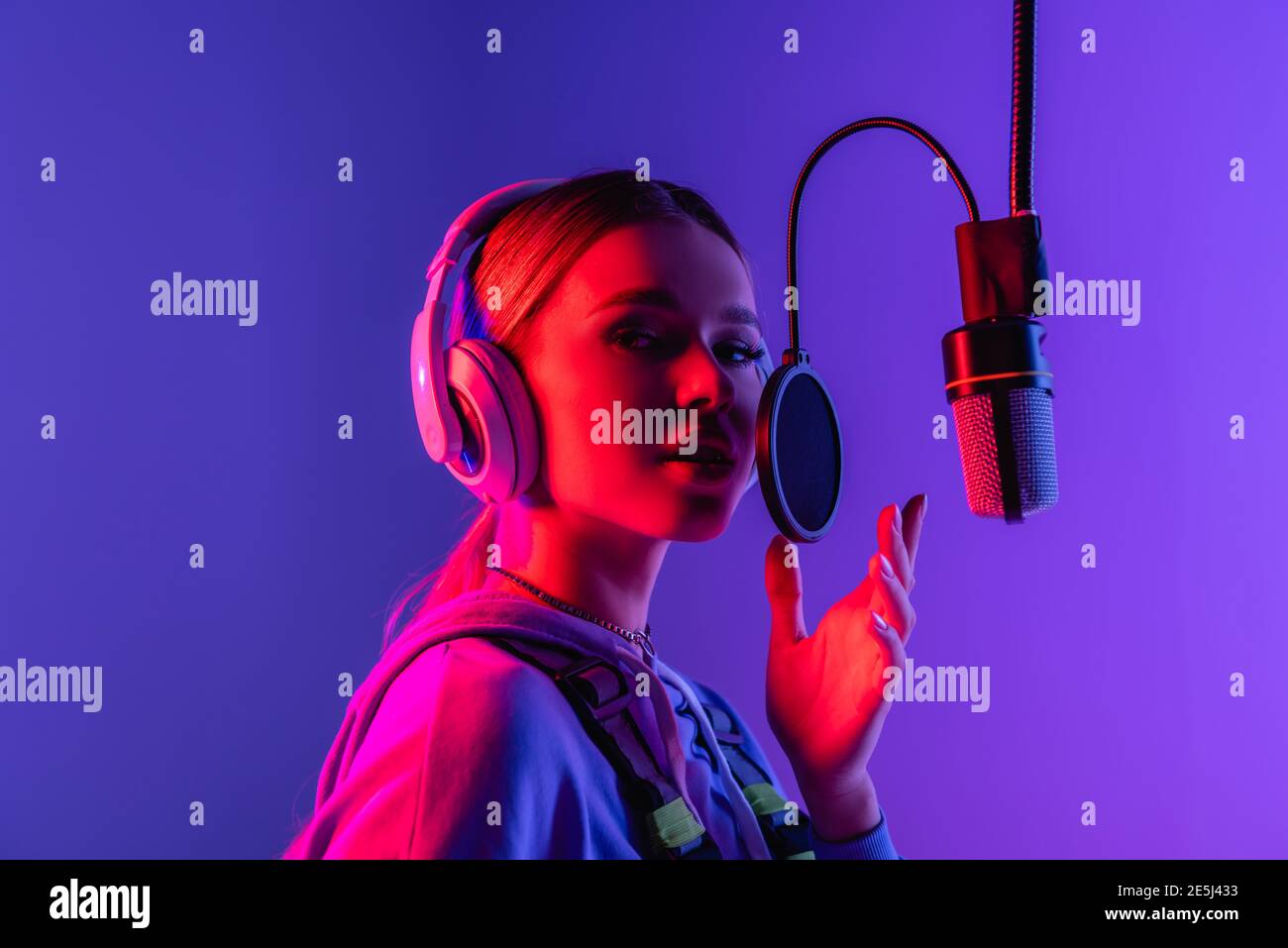 young singer in wireless headphones singing song in microphone on ...