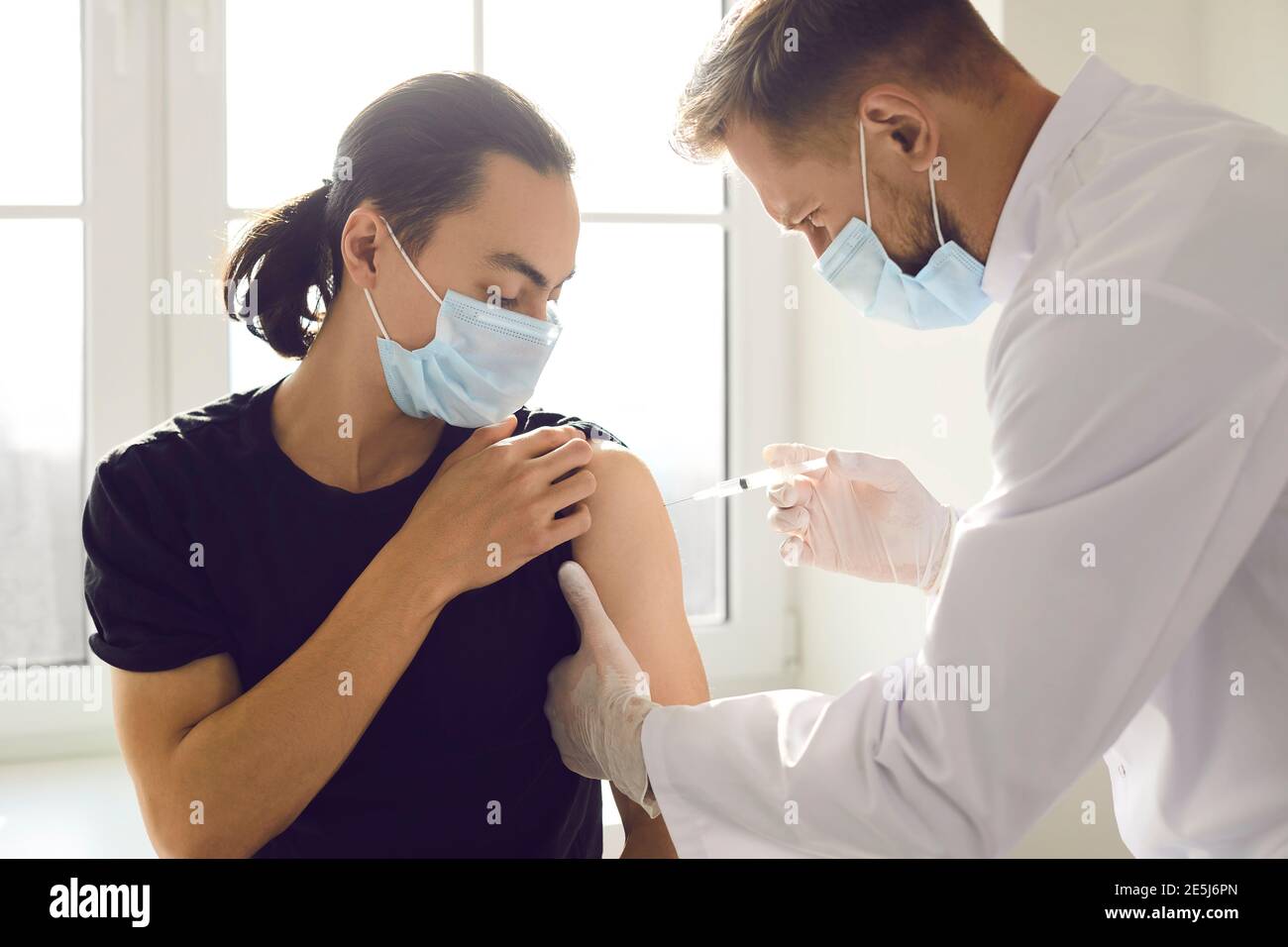 Doctor medical worker in uniform and face mask making injection ...