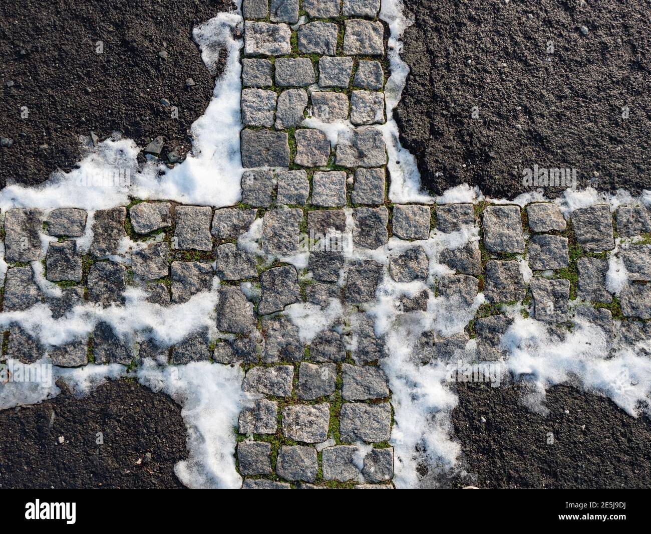 Cobblestones in pavement covered with snow. The mosaic on the square ...