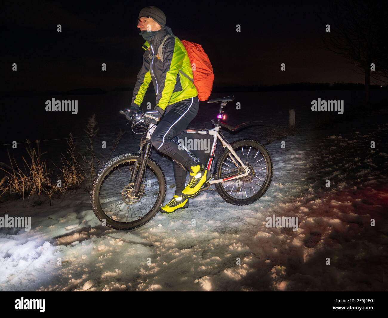 Mountain biker ride alone in snowy winter night. Sportsman properly ...