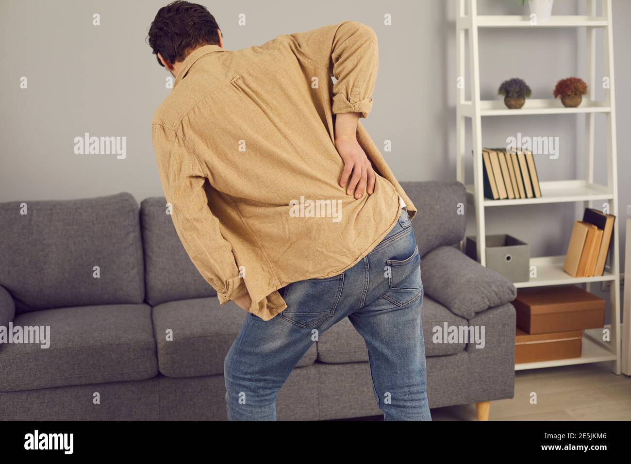 Back view of man with rheumatism feeling intense pain and touching his ...