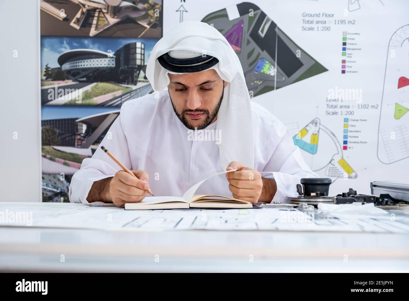 Arab male architect reading a book while working Stock Photo - Alamy