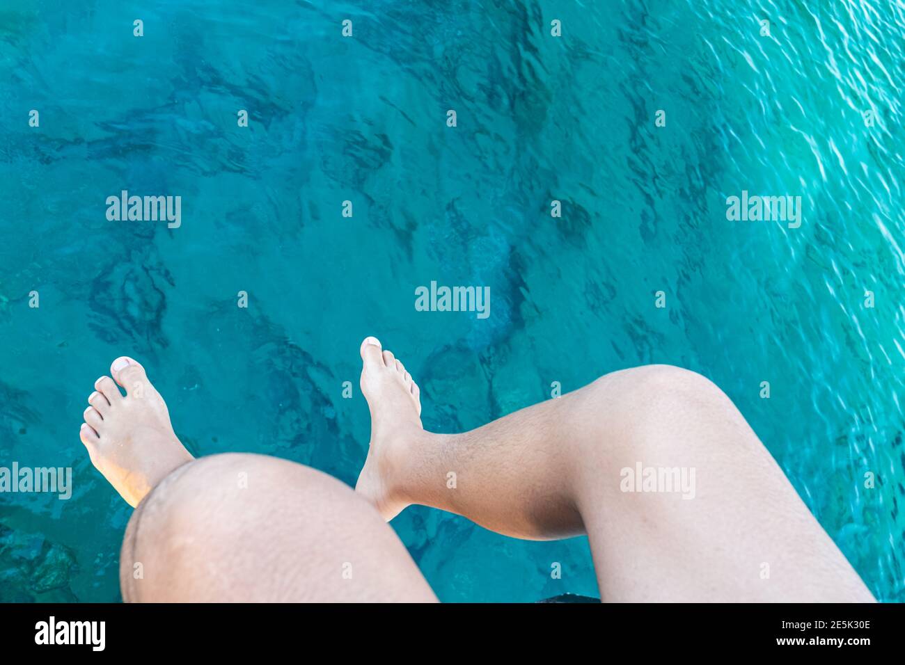 Young man sitting on the floor and He puts his feet above the water ...