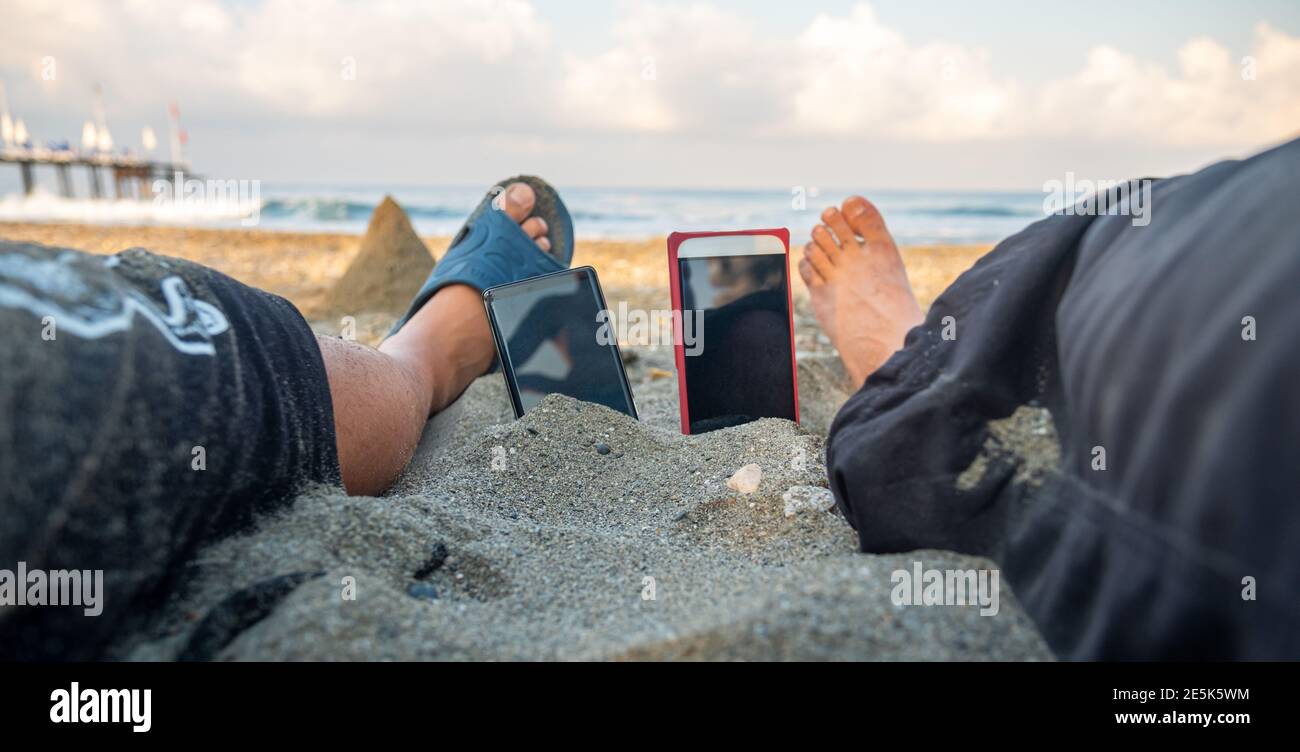 Two legs and smart phone on the sand Stock Photo - Alamy