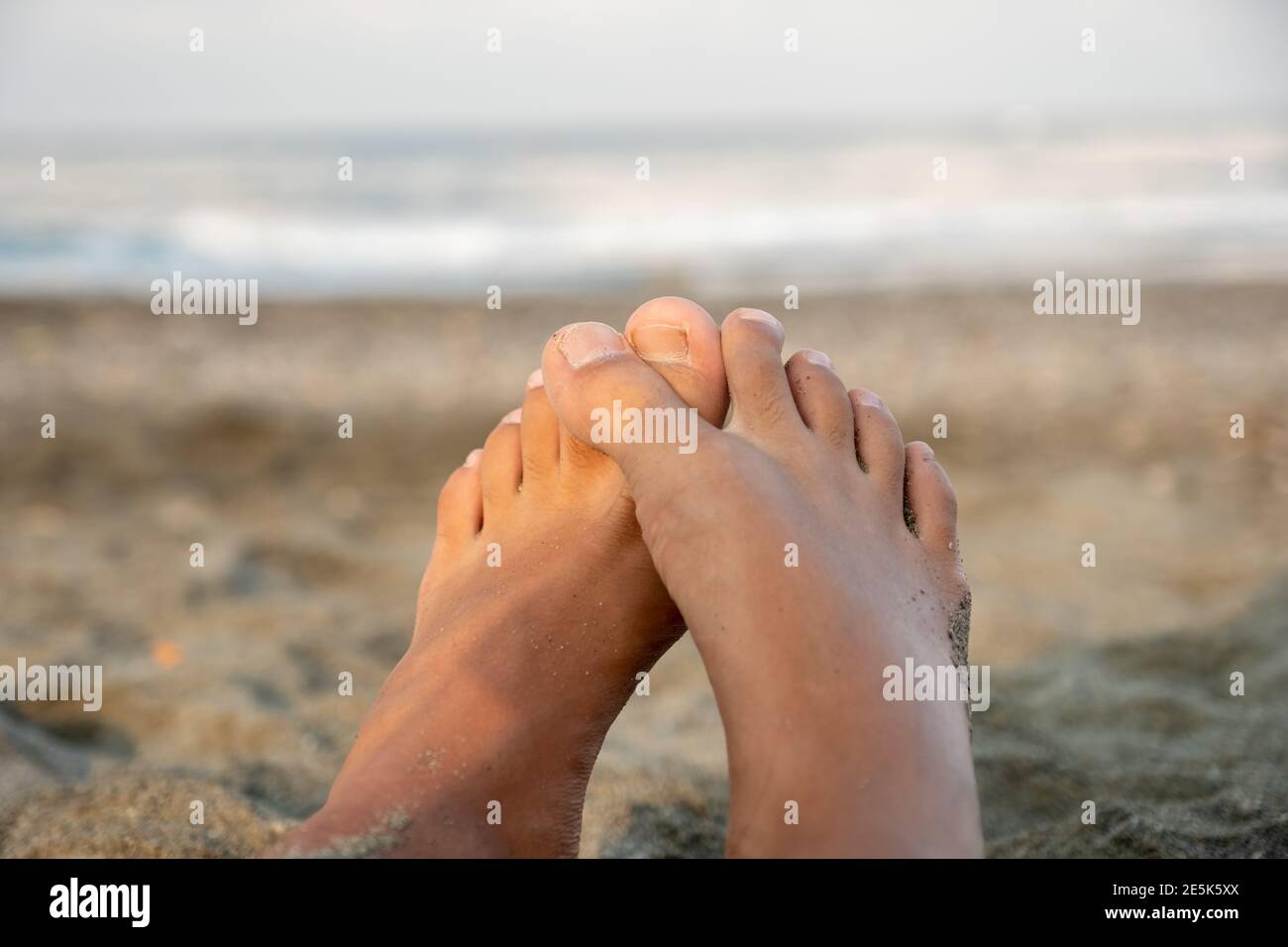 Man crossing his legs on the beach Stock Photo - Alamy