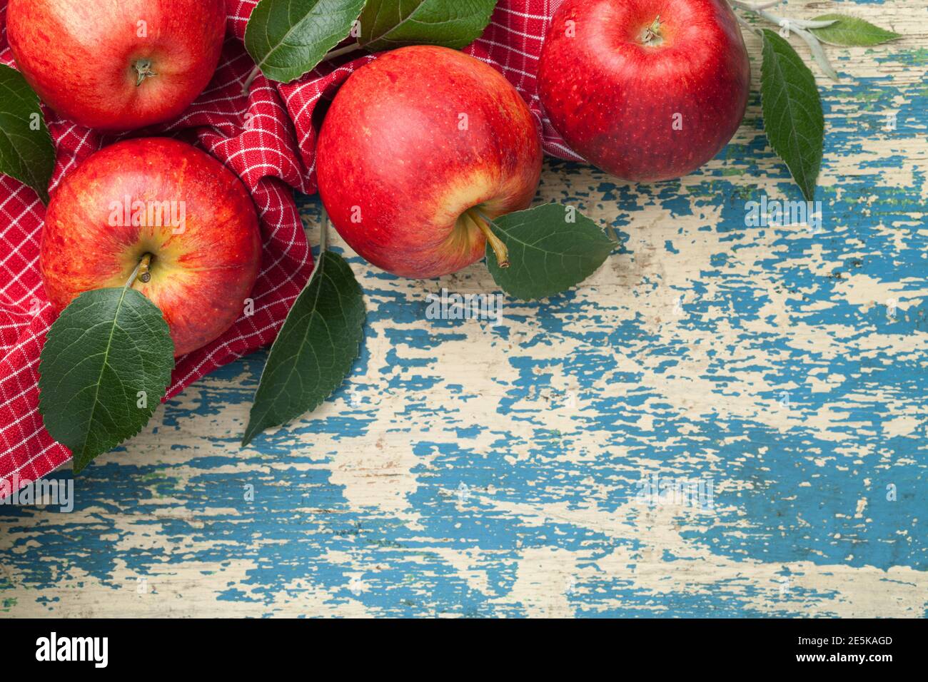 Red apples, fresh green leaves composition on red and white checkered ...