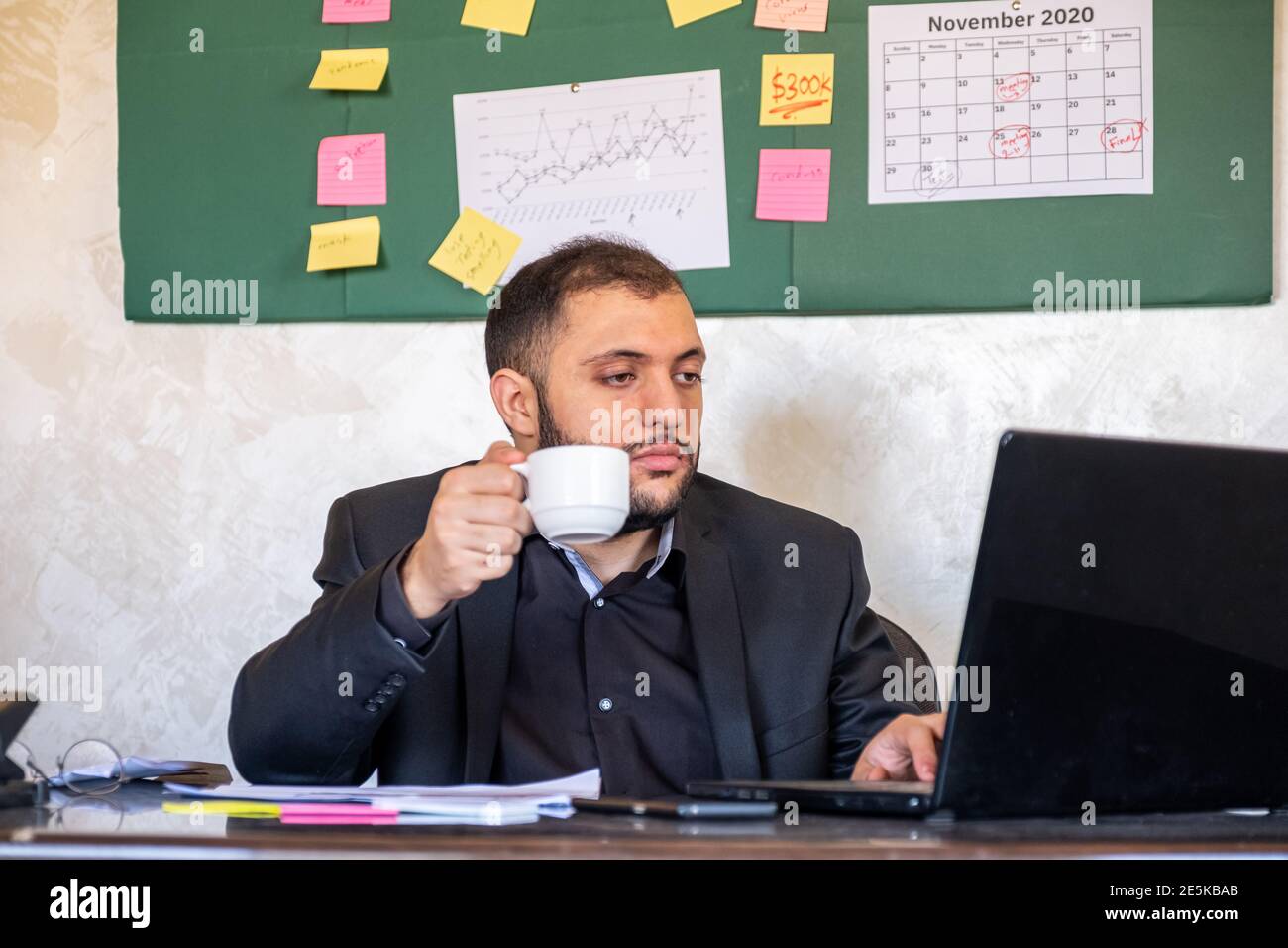 man drinking while working in his office Stock Photo - Alamy