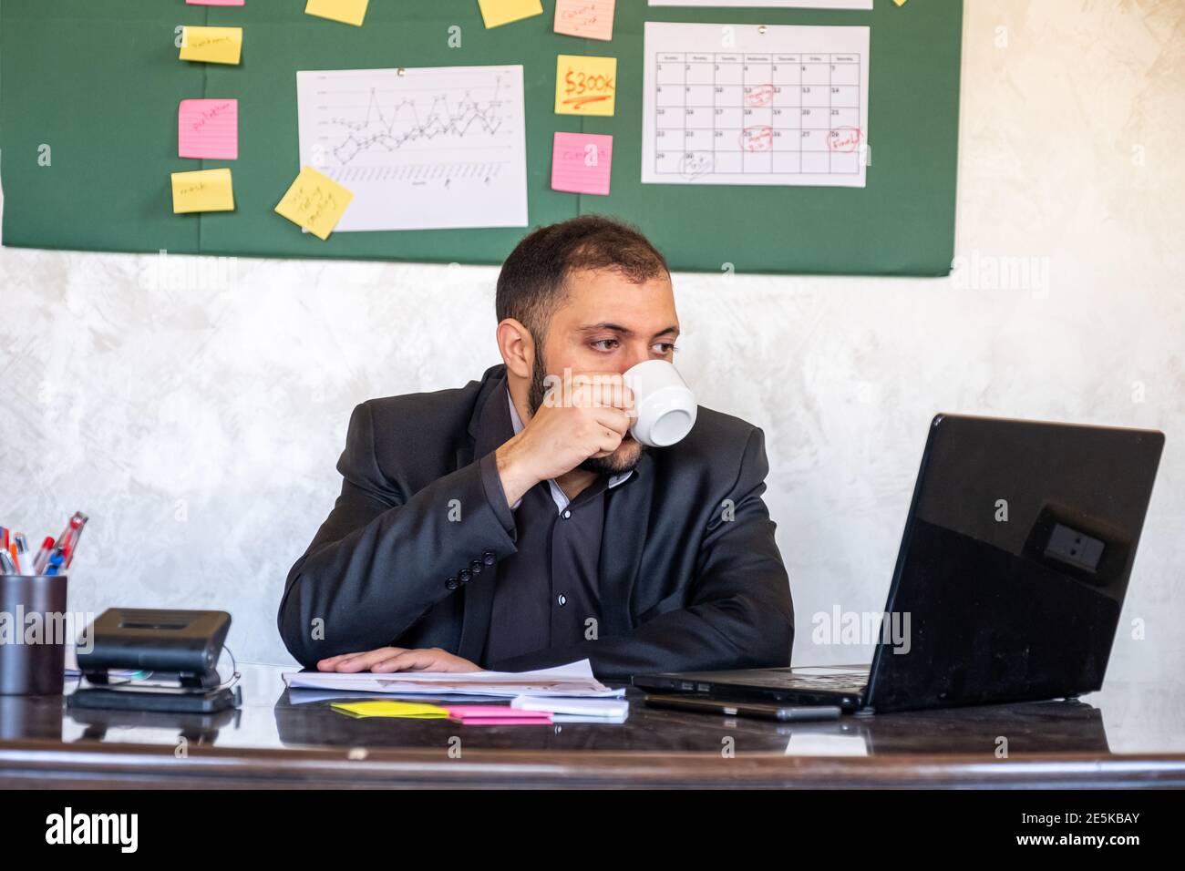 man drinking while working in his office Stock Photo - Alamy