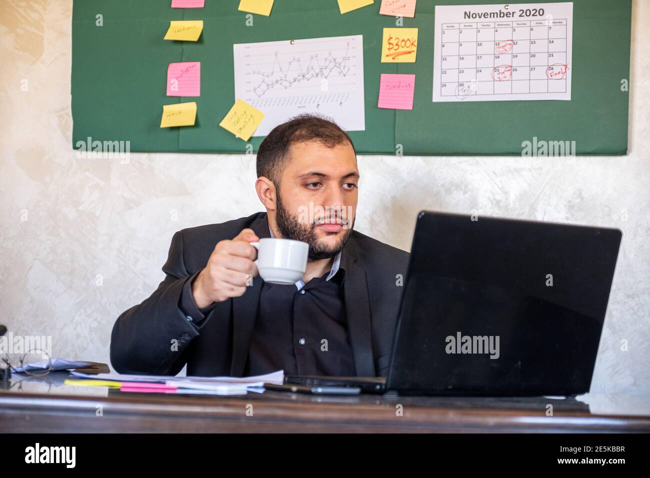 man drinking while working in his office Stock Photo - Alamy