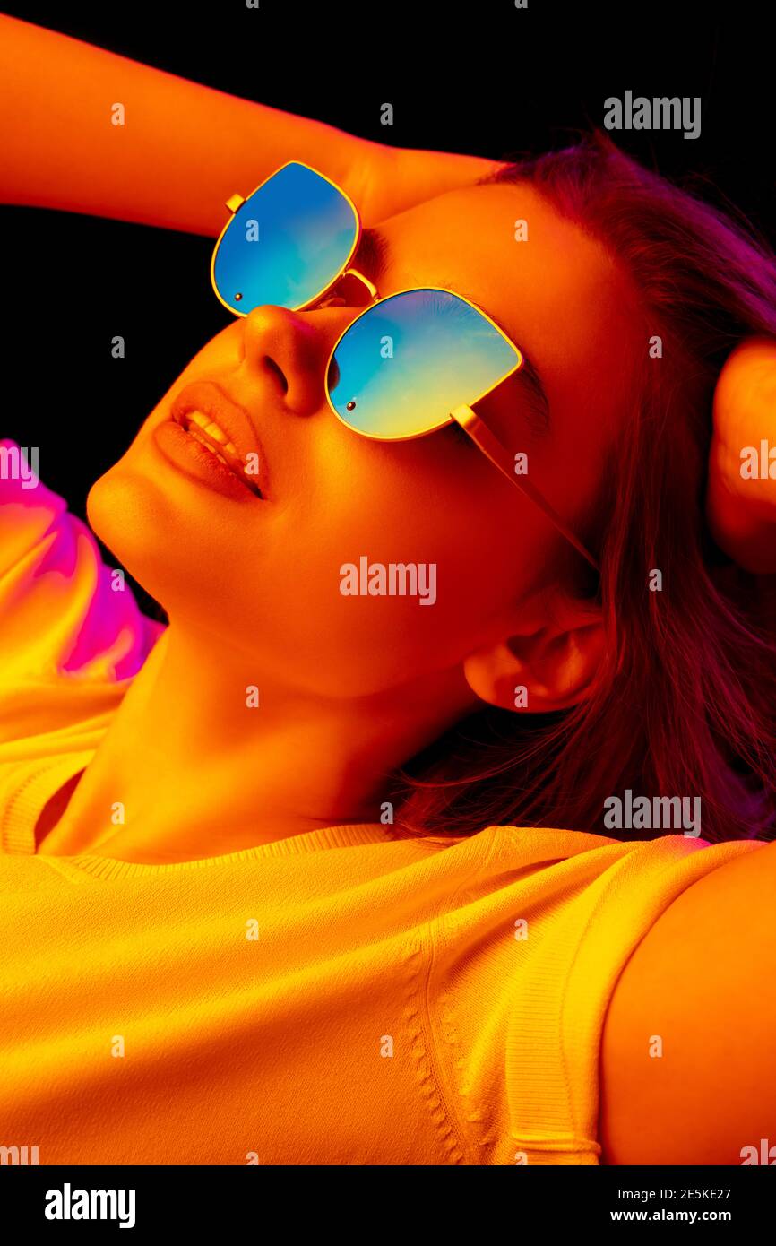 Chill. Caucasian woman's portrait on black studio background in orange ...