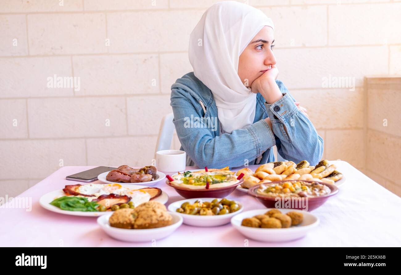 Muslim girl is thinking while eating her breakfast Stock Photo - Alamy