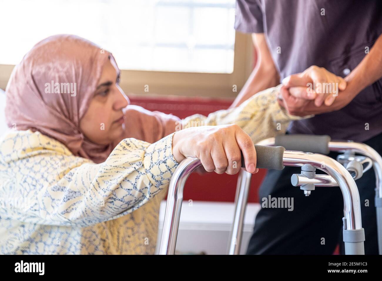 muslim woman with disability is trying to stand with her son's help ...