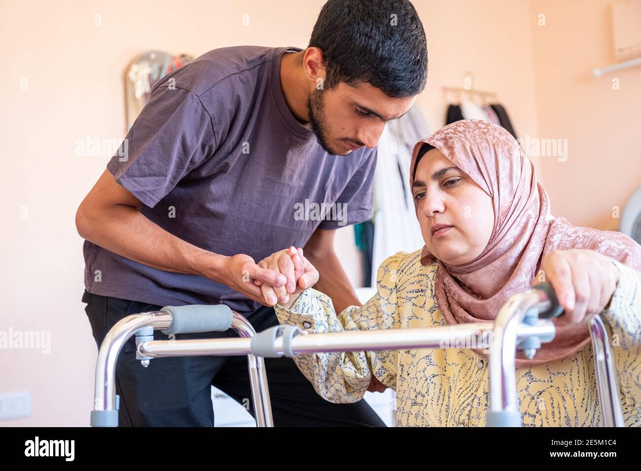 muslim woman with disability is trying to stand with her son's help ...