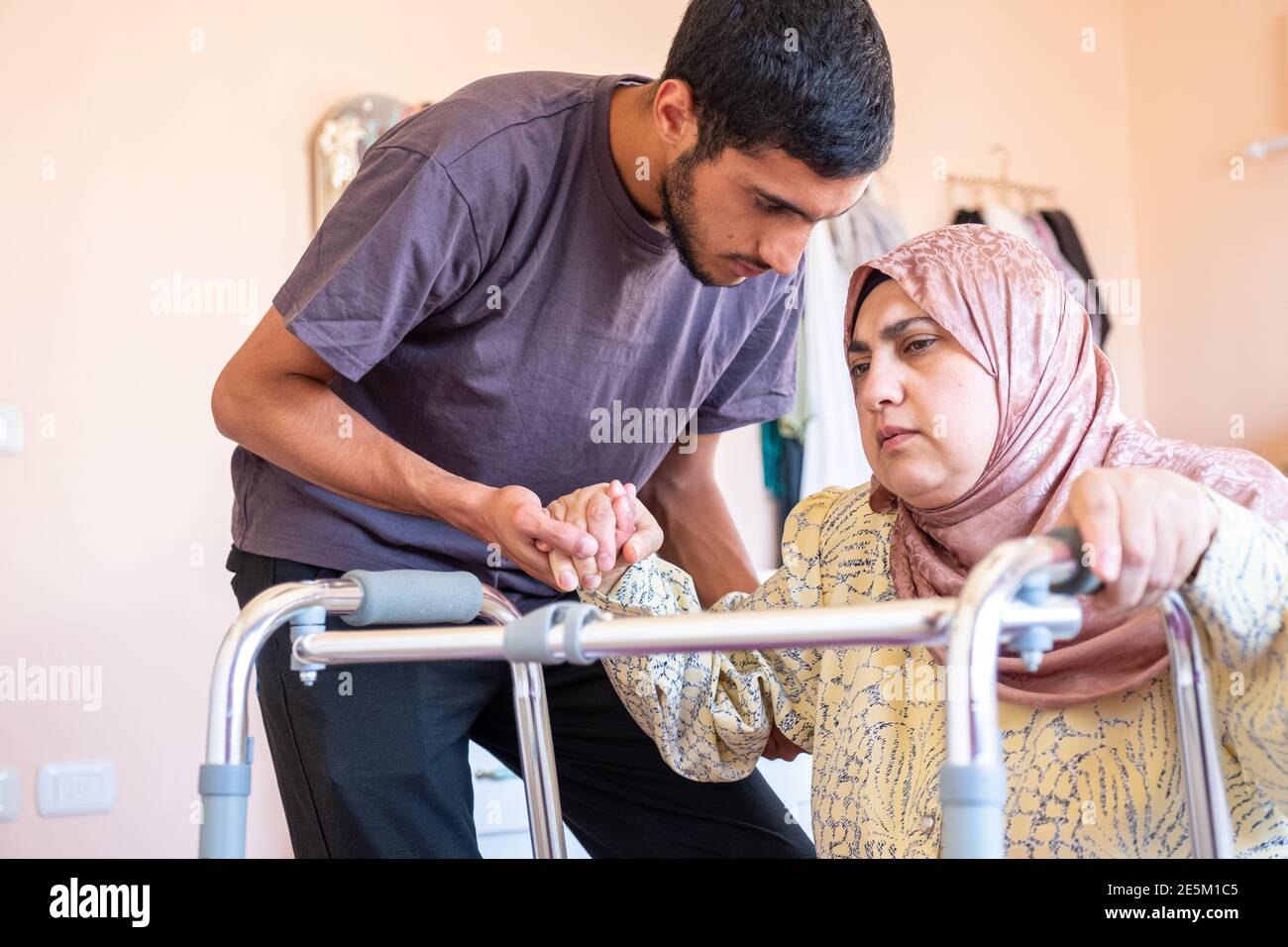 muslim woman with disability is trying to stand with her son's help ...