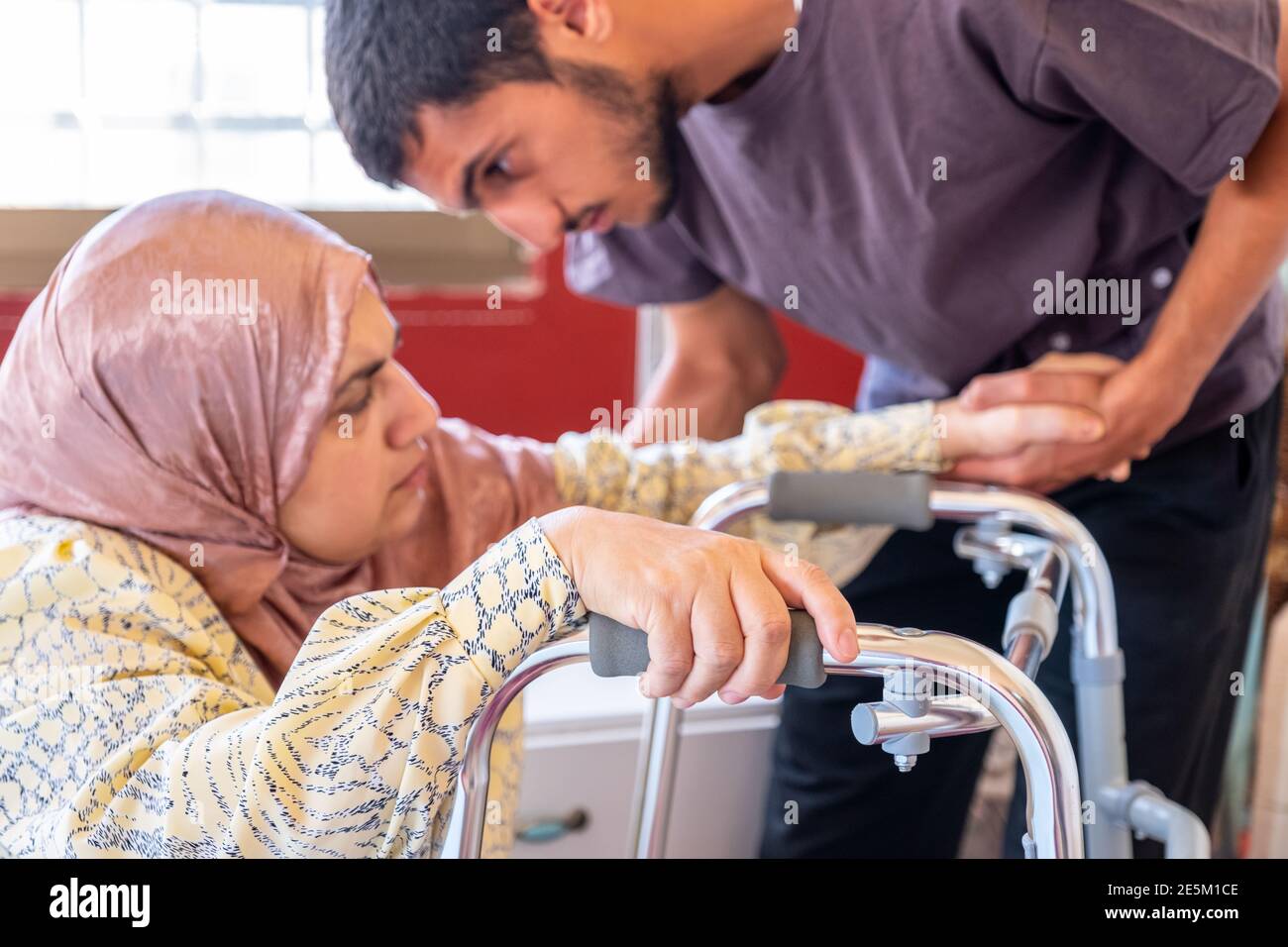 muslim woman with disability is trying to stand with her son's help ...