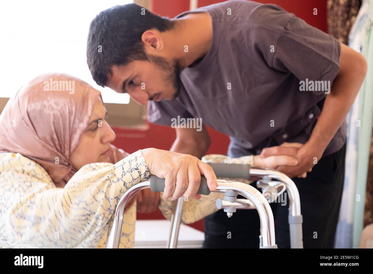 muslim woman with disability is trying to stand with her son's help ...