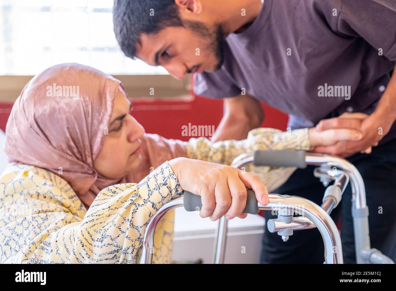 muslim woman with disability is trying to stand with her son's help ...
