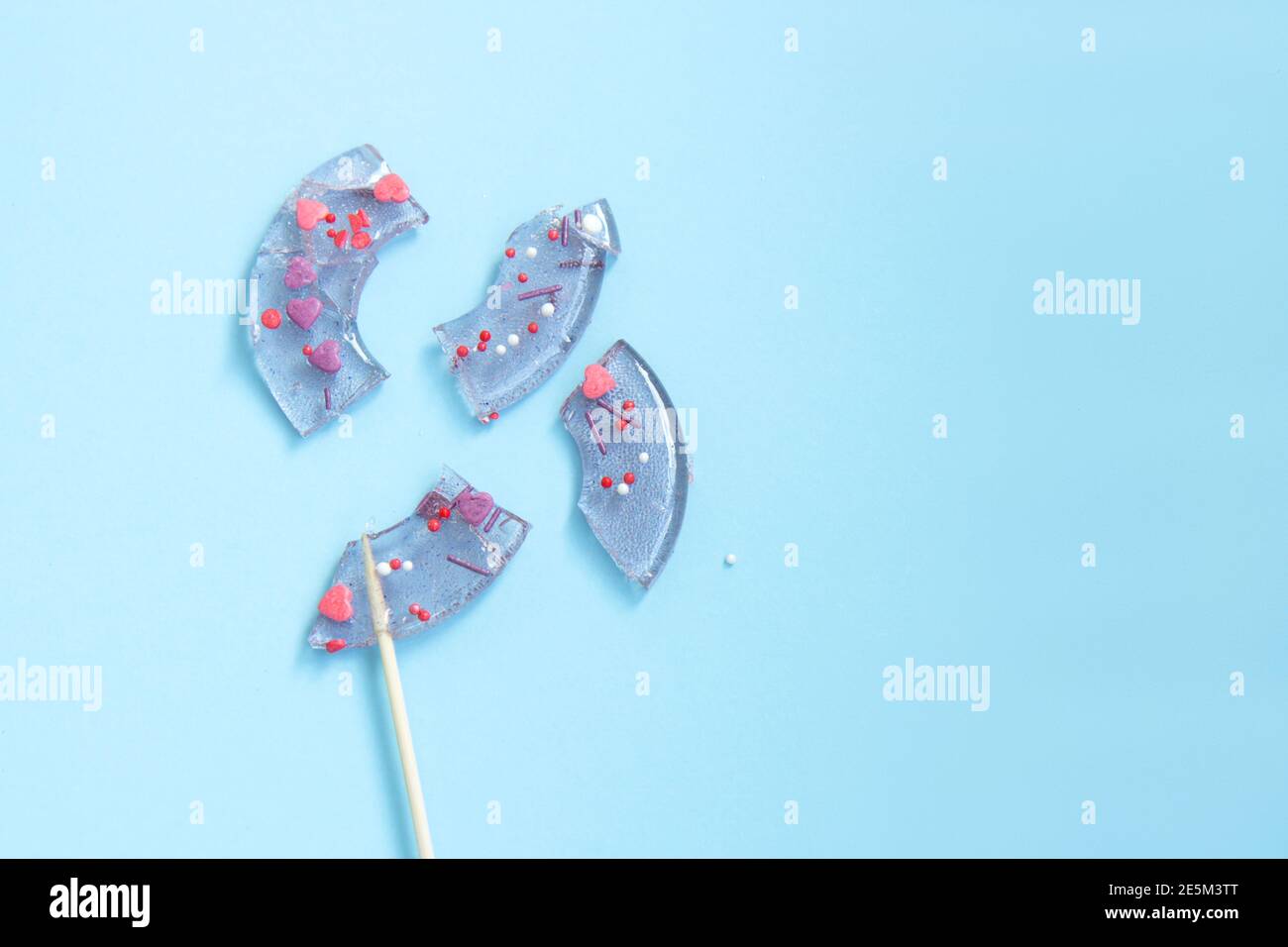 Broken in pieces transparent candy with little hearts on a stick ...