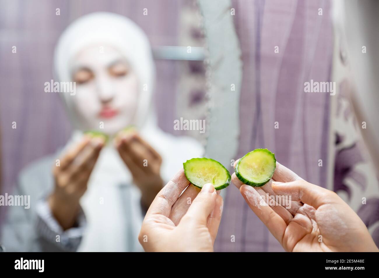 Muslim woman taking care of her skin and putting cucumber on her eyes ...
