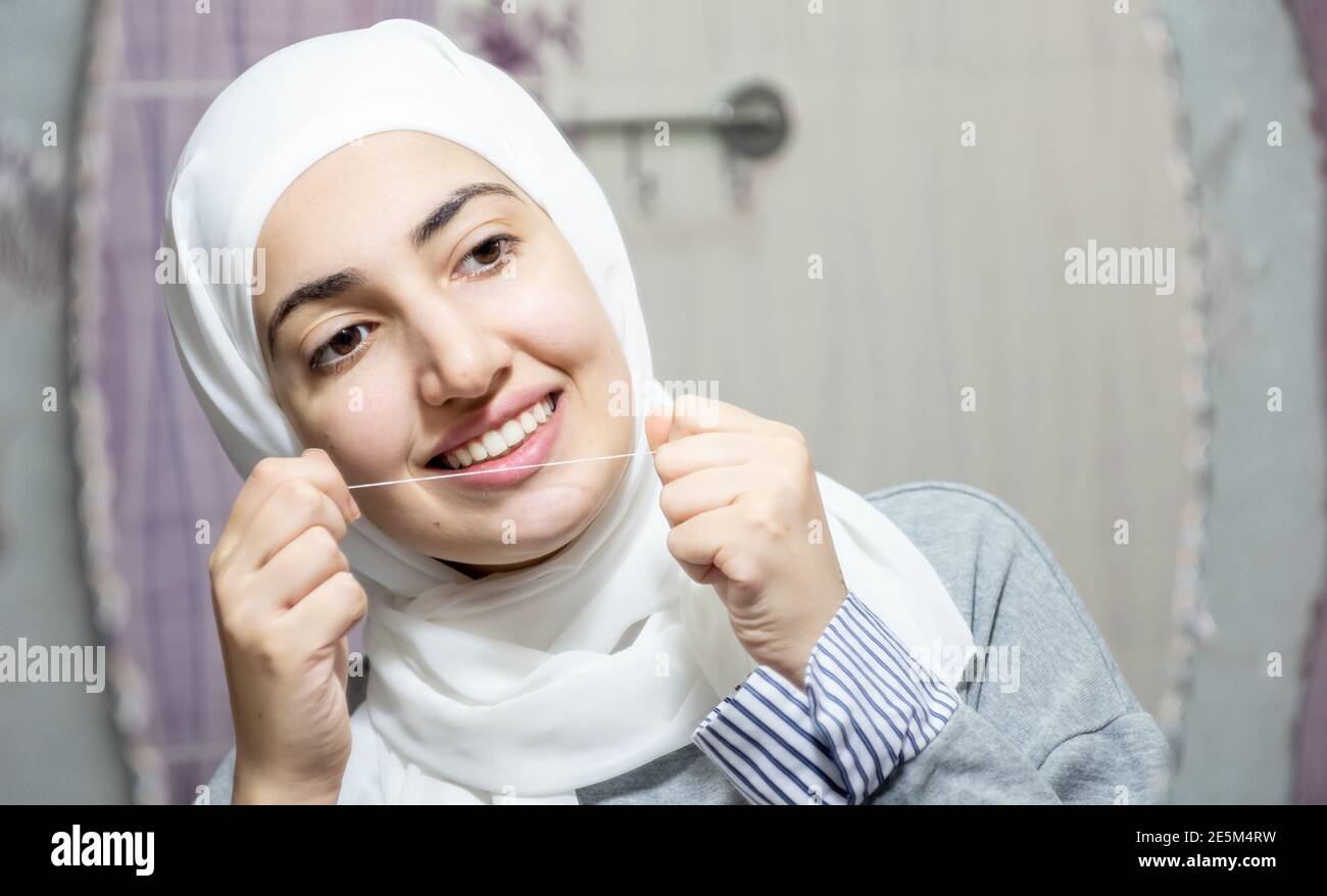 Arabic muslim woman cleaning her teeth with dental floss Stock Photo ...