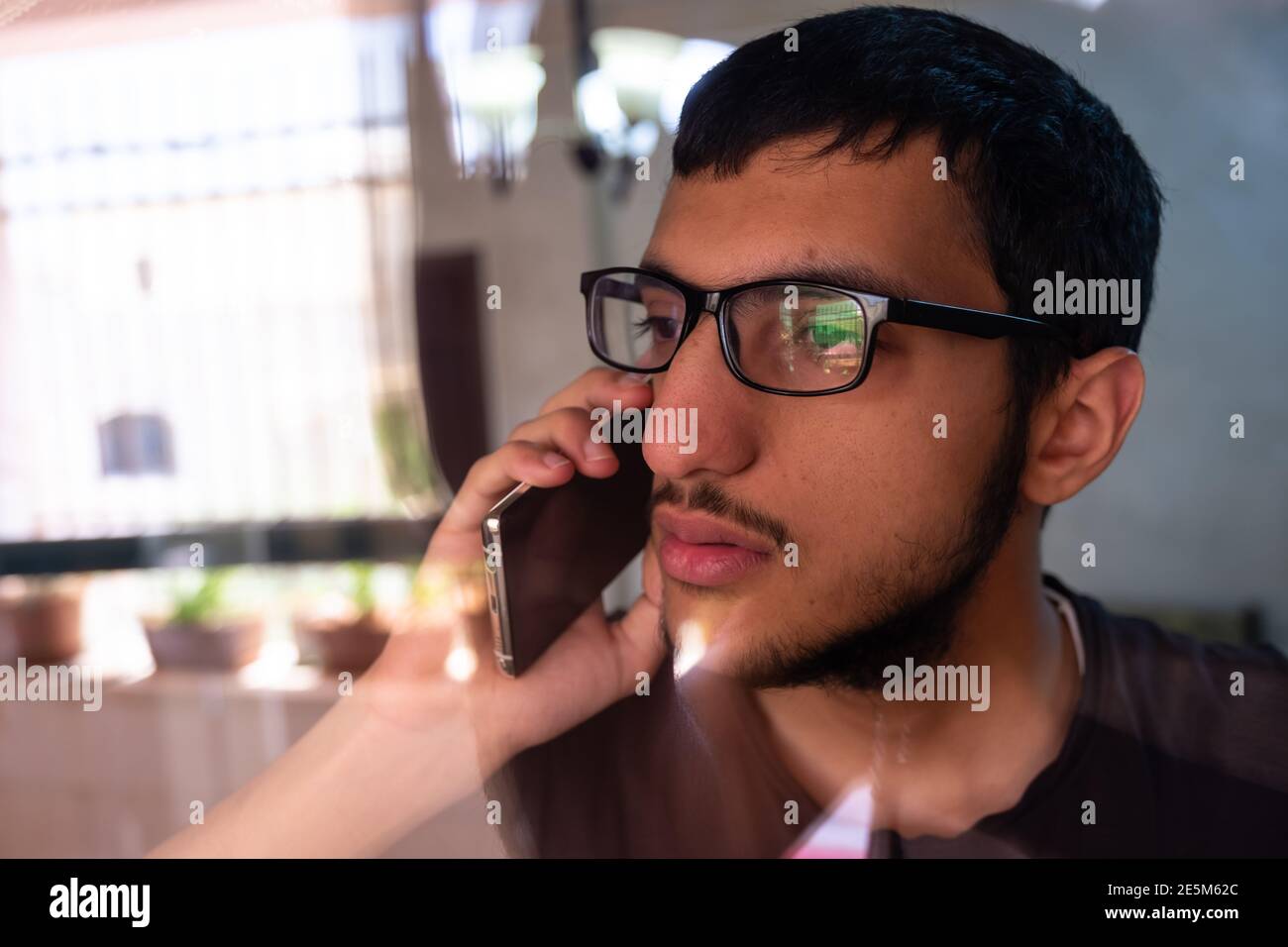 Guy talking on the phone while looking from window glass Stock Photo ...