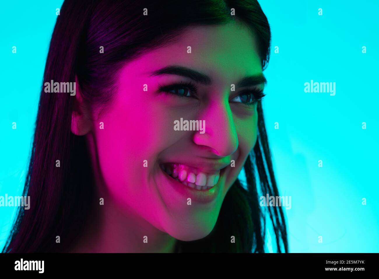 Cheerful. Close up brunette woman's portrait isolated on blue studio ...