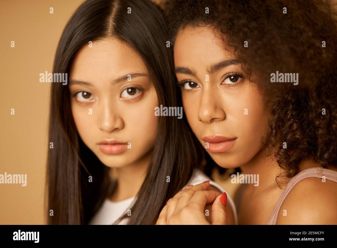 Face closeup of two beautiful mixed race young women with perfect skin ...