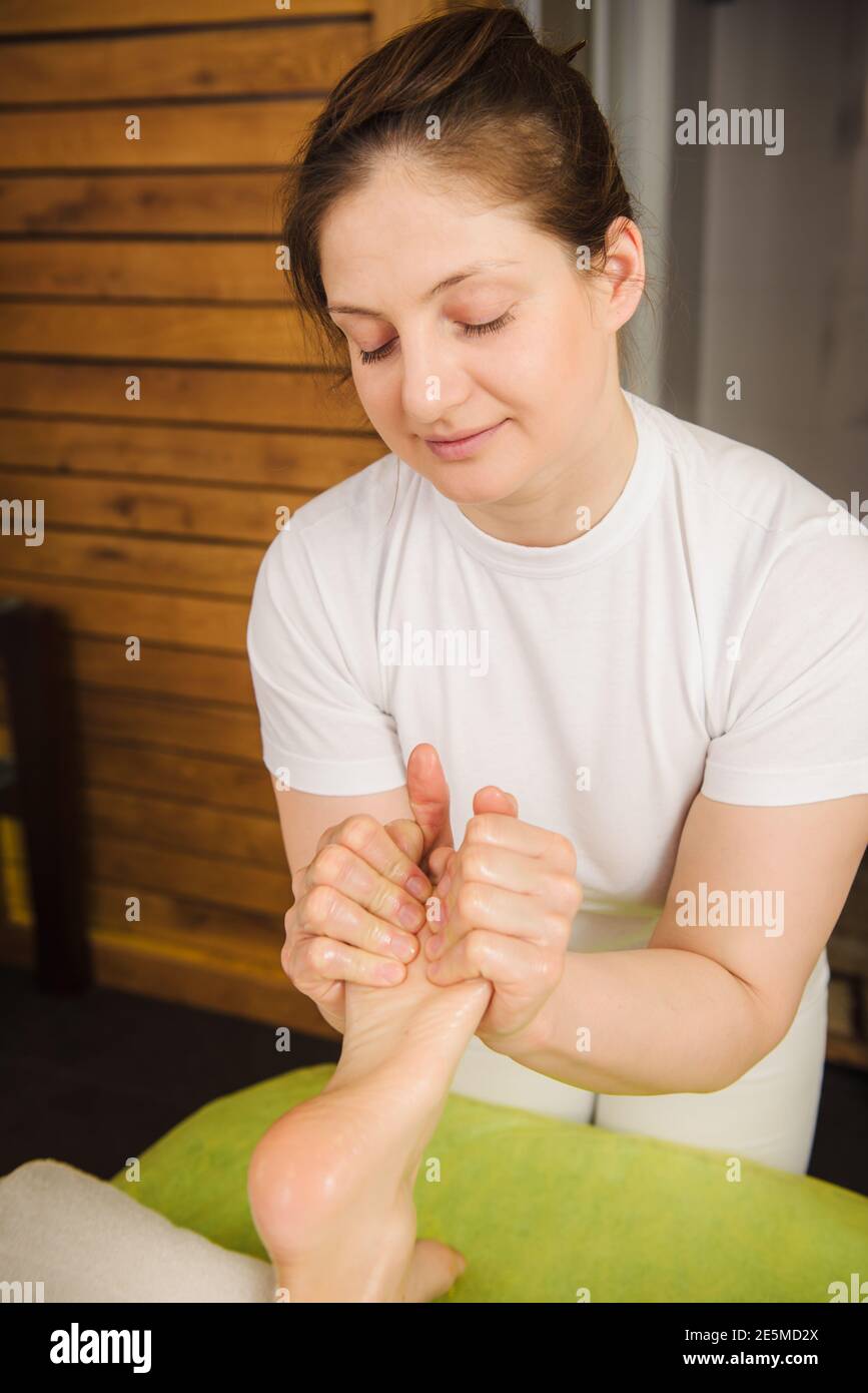 Traditional foot massage. Beautiful woman enjoying a treatment in a spa ...