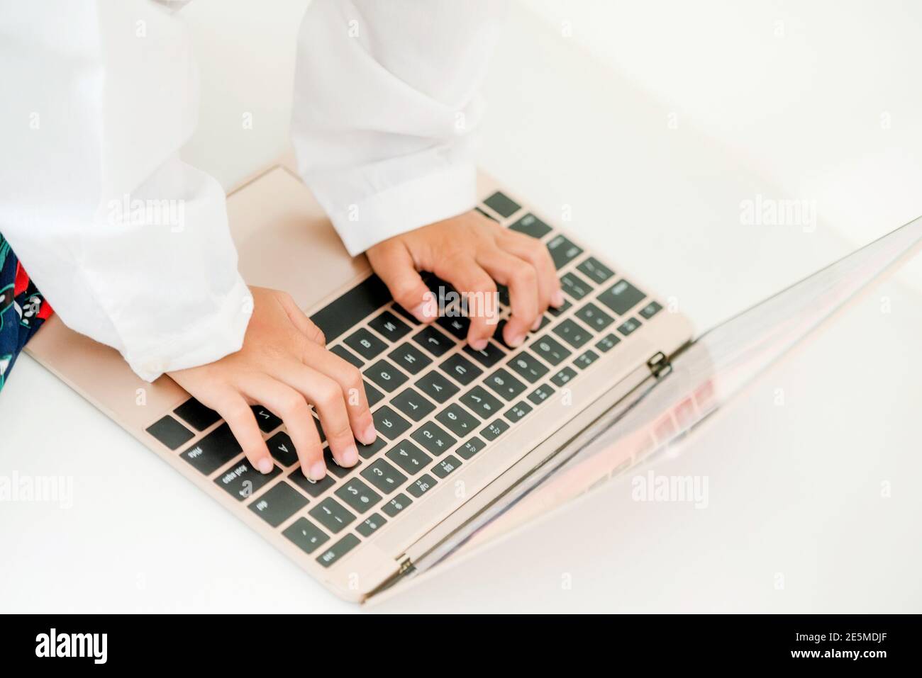 Little kid using laptop computer sitting on white background. Close up ...