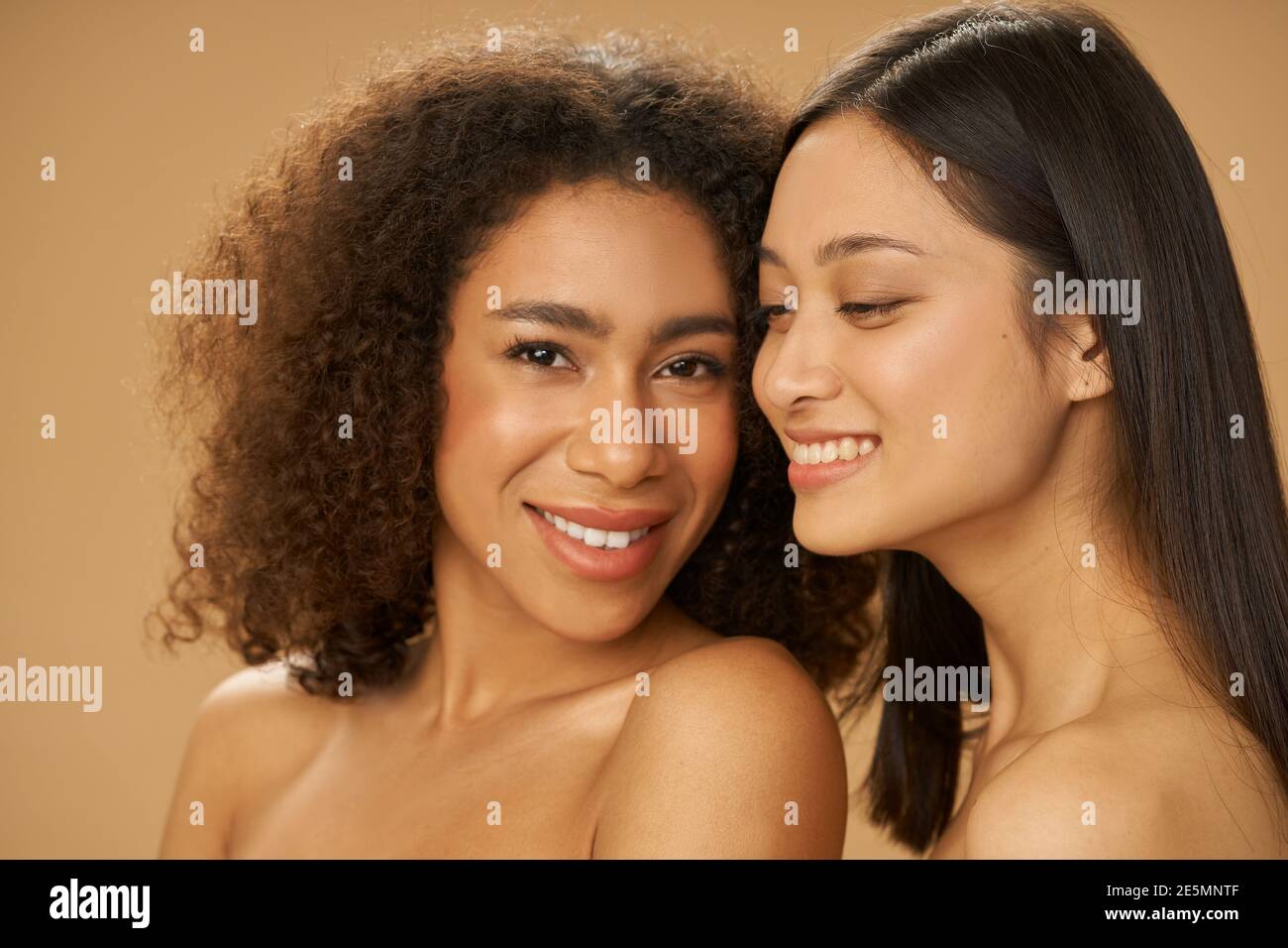 Portrait of two pretty mixed race young women with perfect smile posing ...