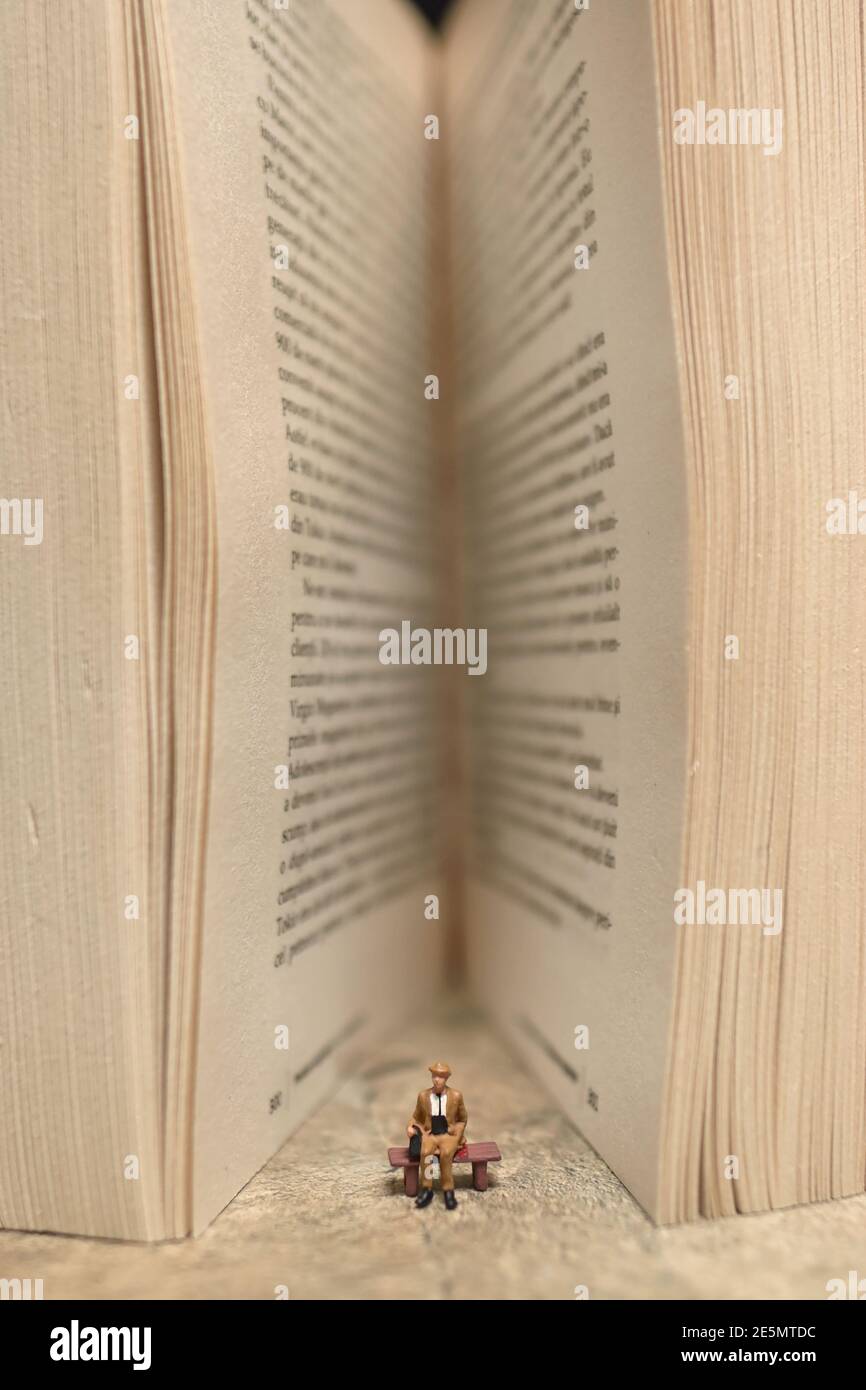 Conceptual Miniature Man Sitting On Bench In Library Stock Photo - Alamy