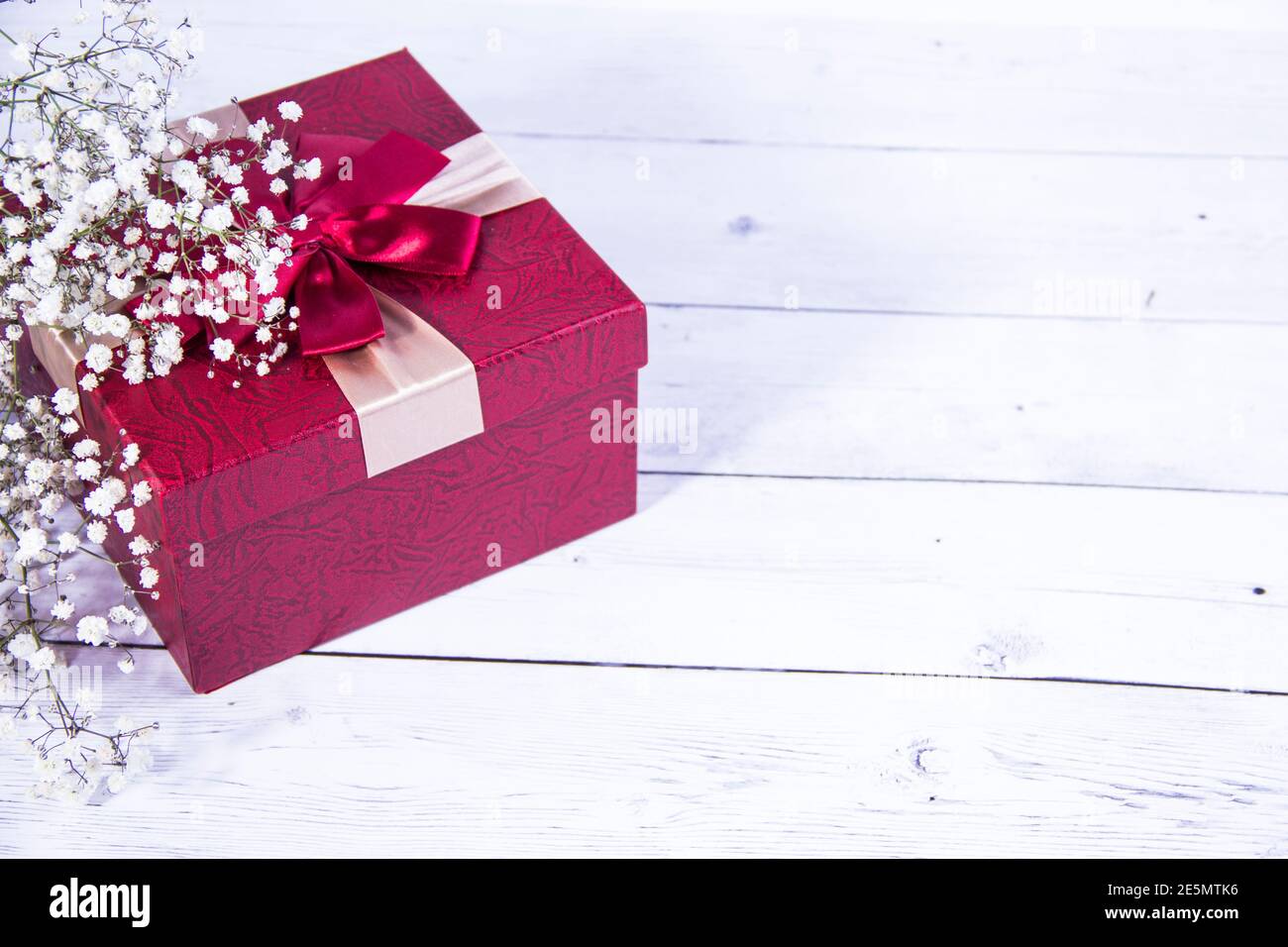 Red color gift box with flower on blue wooden background Stock Photo ...