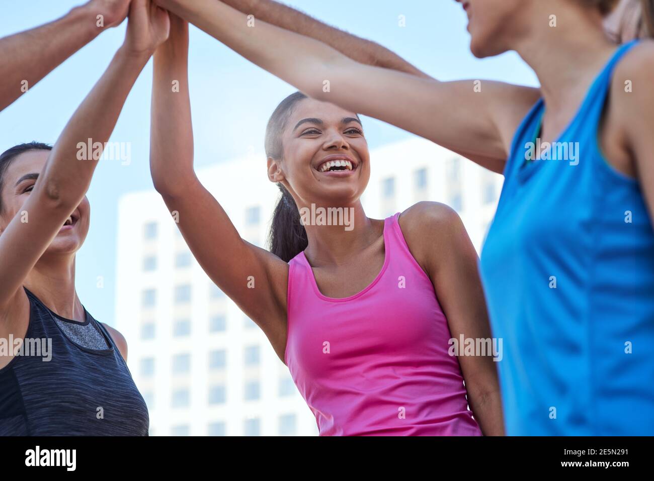 Happy young sport team holding raised hands together Stock Photo - Alamy