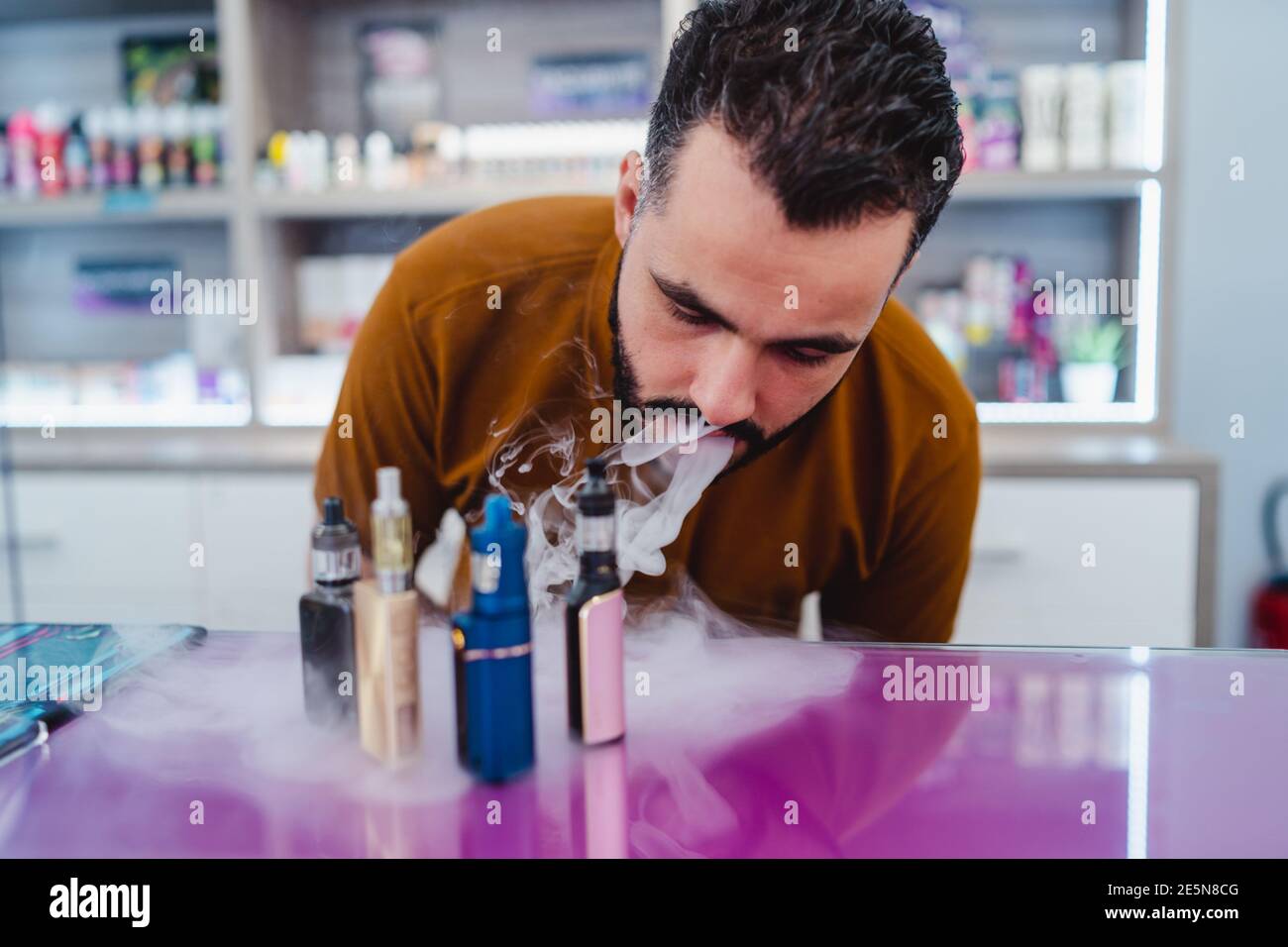Vape addict blowing smoke in a store Stock Photo - Alamy