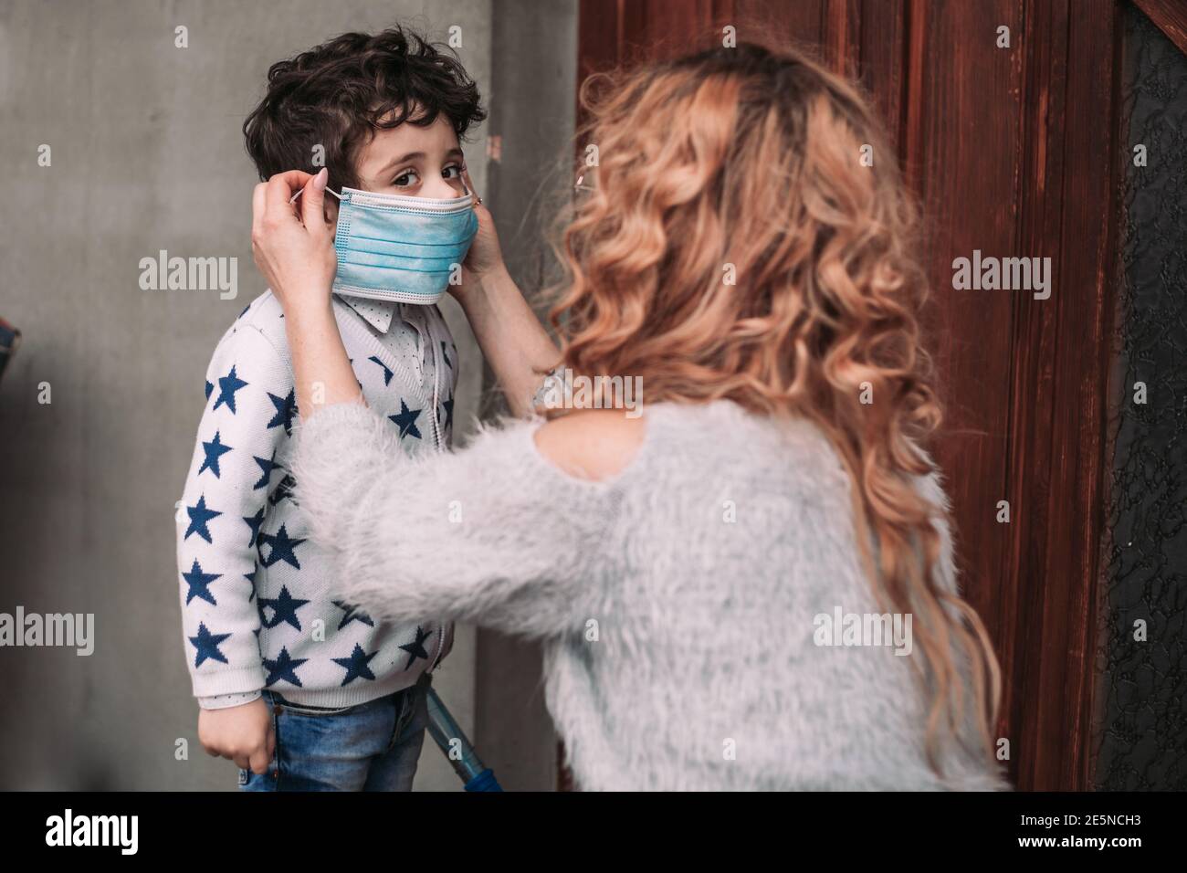 Mom putting on a mask on her son's face. Covid prevention Stock Photo ...