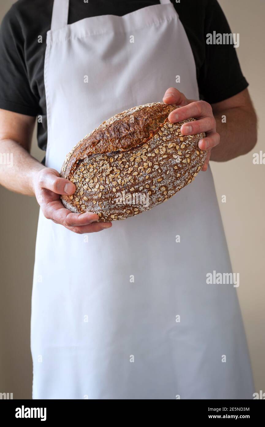 Close-up at bakers hands holding a loaf of organic sourdough bread in ...