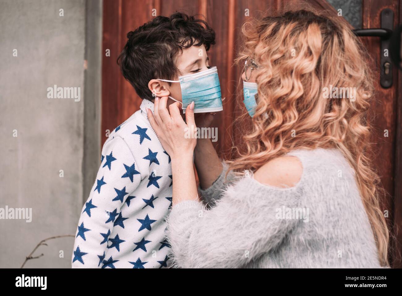 Mom putting on a mask on her sons face. Covid prevention Stock Photo ...