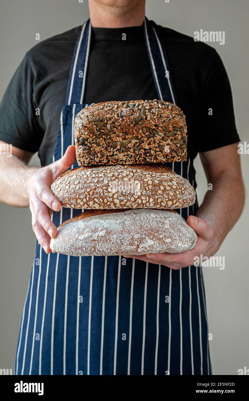 Close-up at bakers hands holding a selection of organic loafs of ...