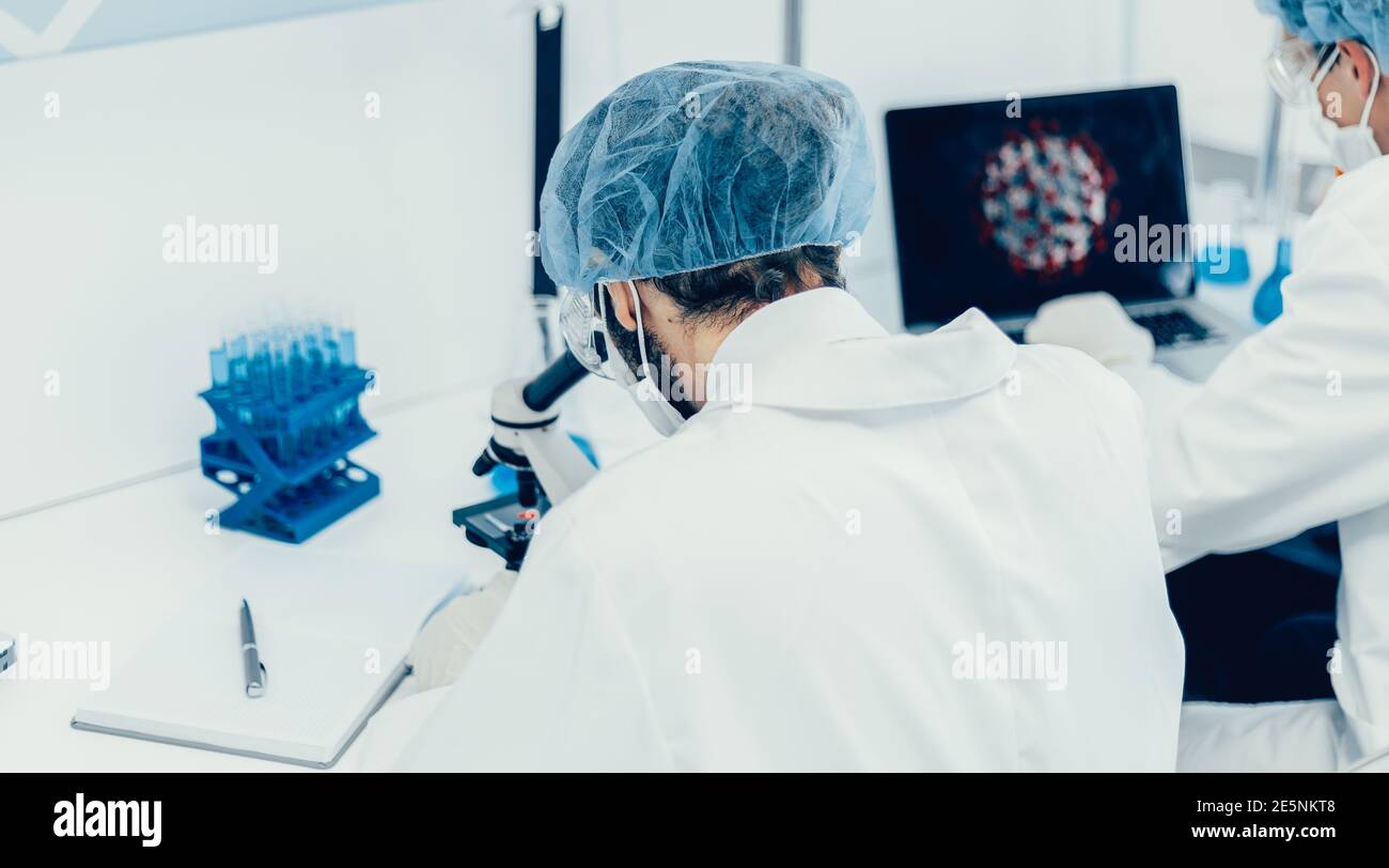 close up. scientist looking at control samples through a microscope ...